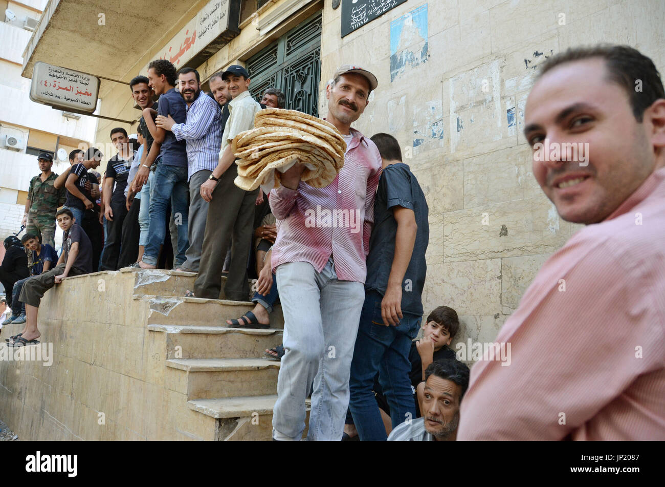 DAMASCUS, Syria - Customers line up in front of a bakery in Damascus ...