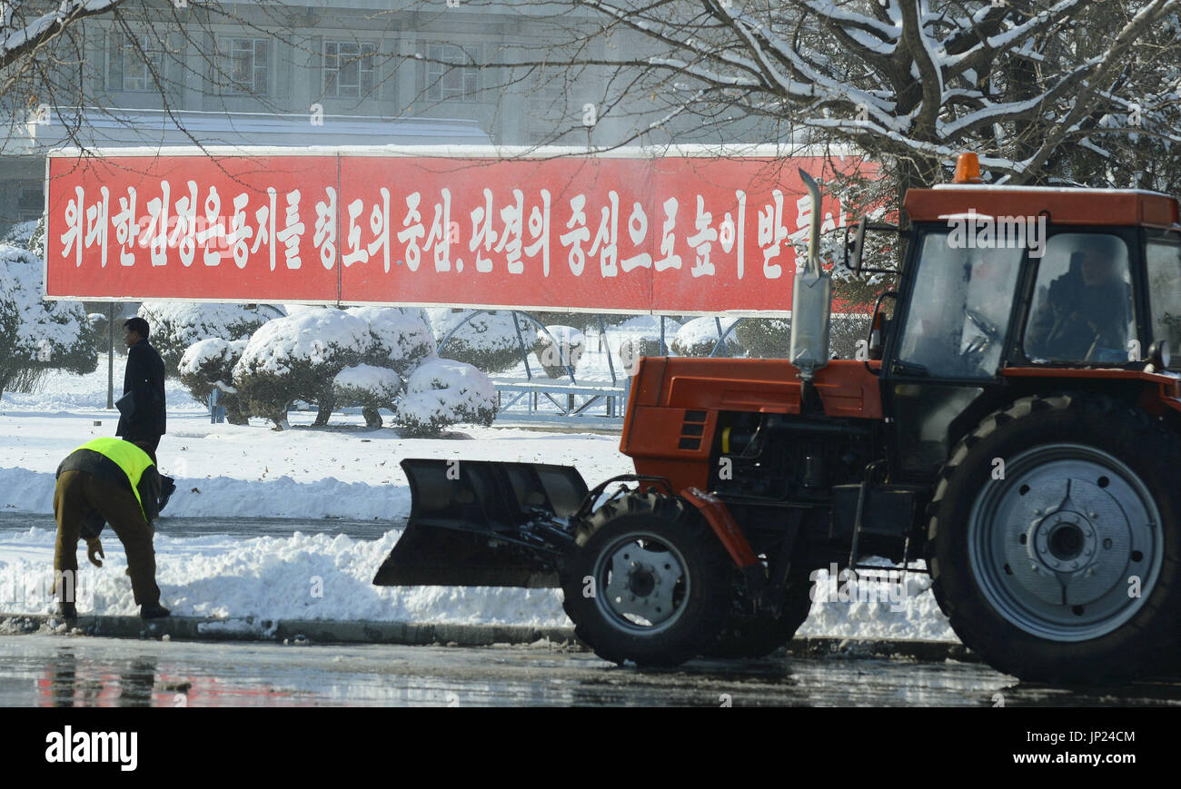 PYONGYANG, North Korea - Workers remove snow on a road in front of a ...