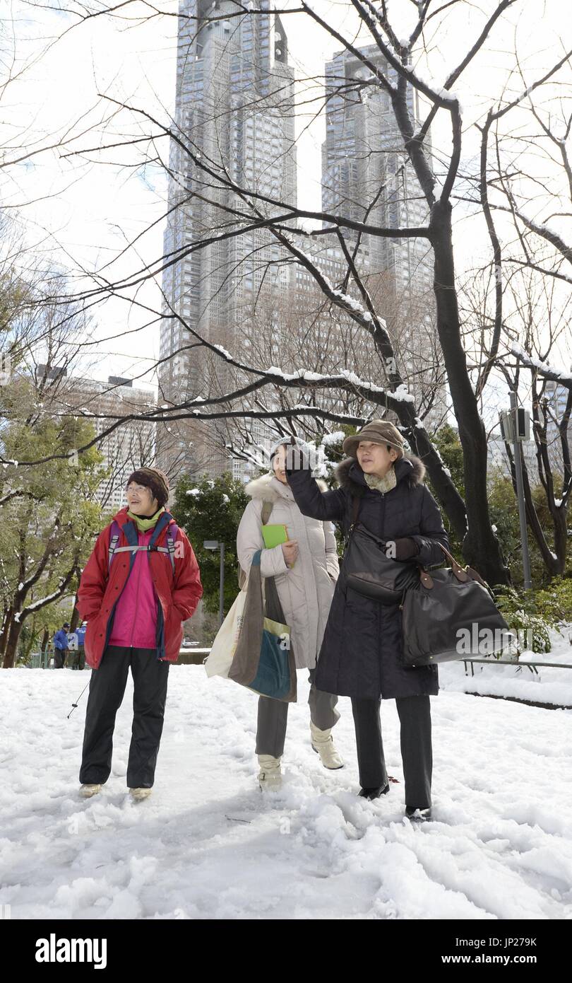 TOKYO, Japan - Women walk in a snow-blanketed park in front of the ...