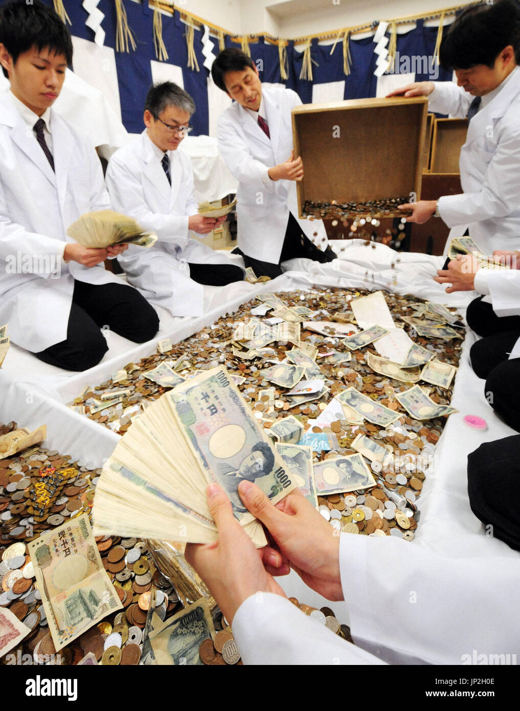 KYOTO, Japan - Bank employees count money thrown into offertory boxes ...