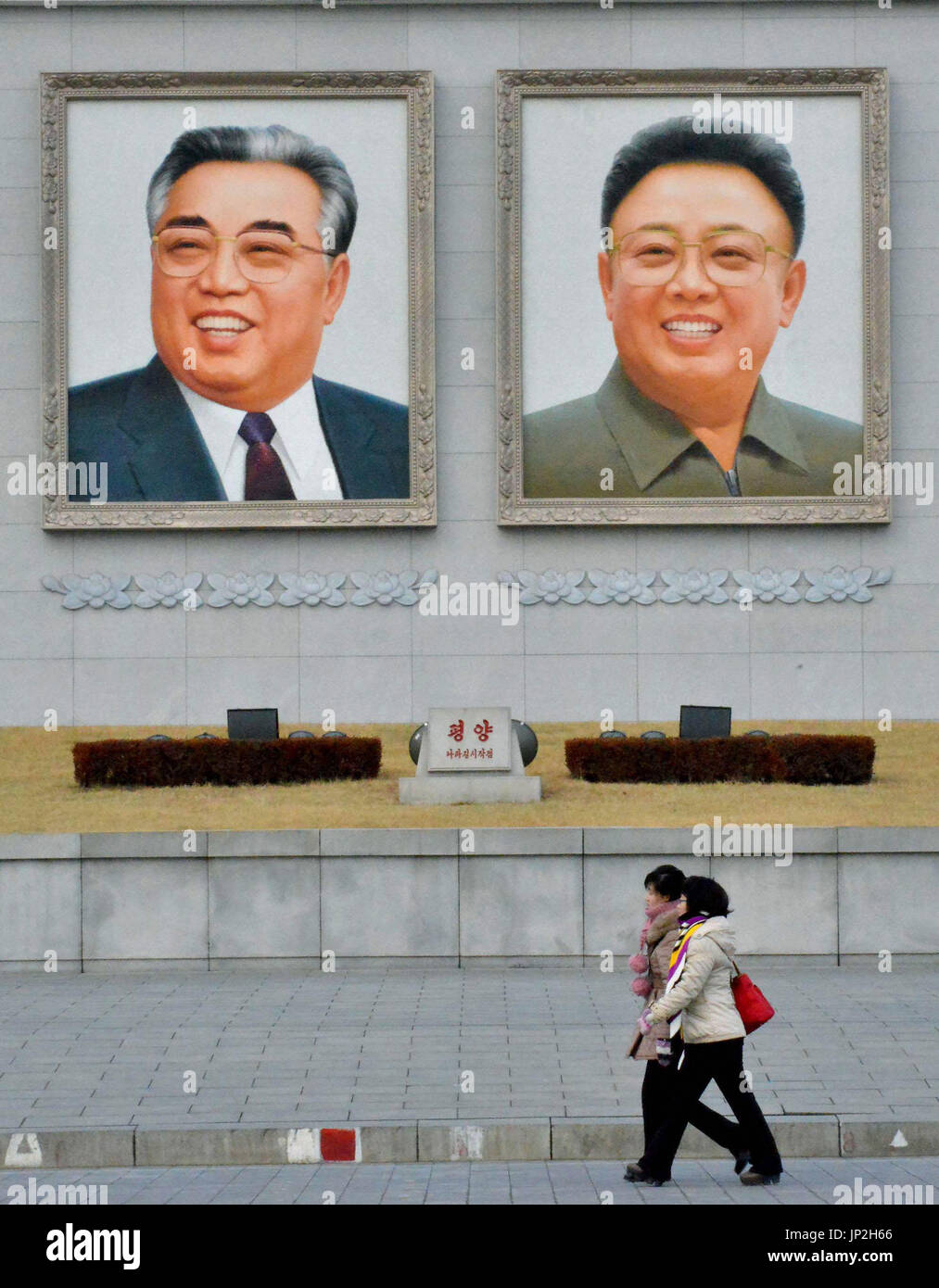 PYONGYANG, North Korea - People walk in front of large portraits of Kim ...