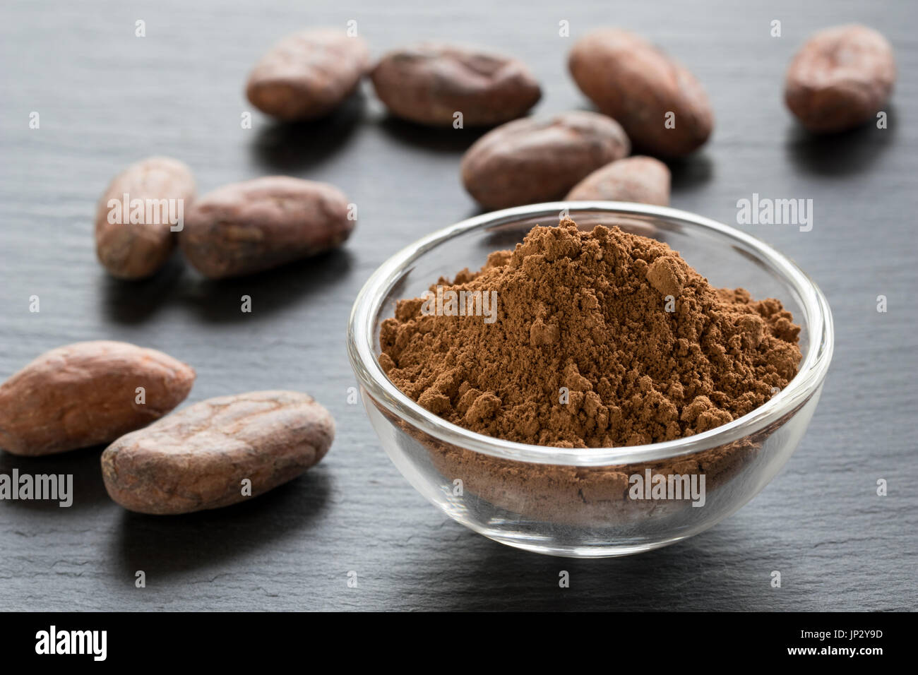 Raw unroasted cocoa powder and raw cacao nibs on a dark background ...