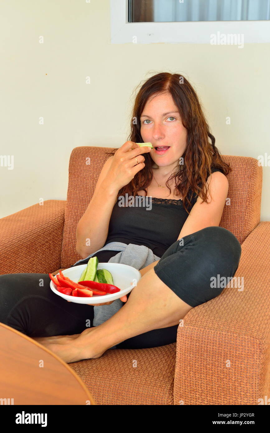 The woman in the chair eating vegetables from a plastic bowl Stock ...