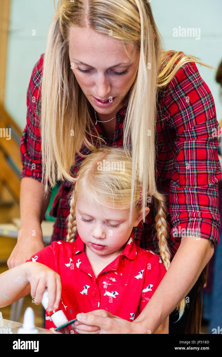 Young Caucasian long blonde haired woman, 30s, mother, leaning over her ...
