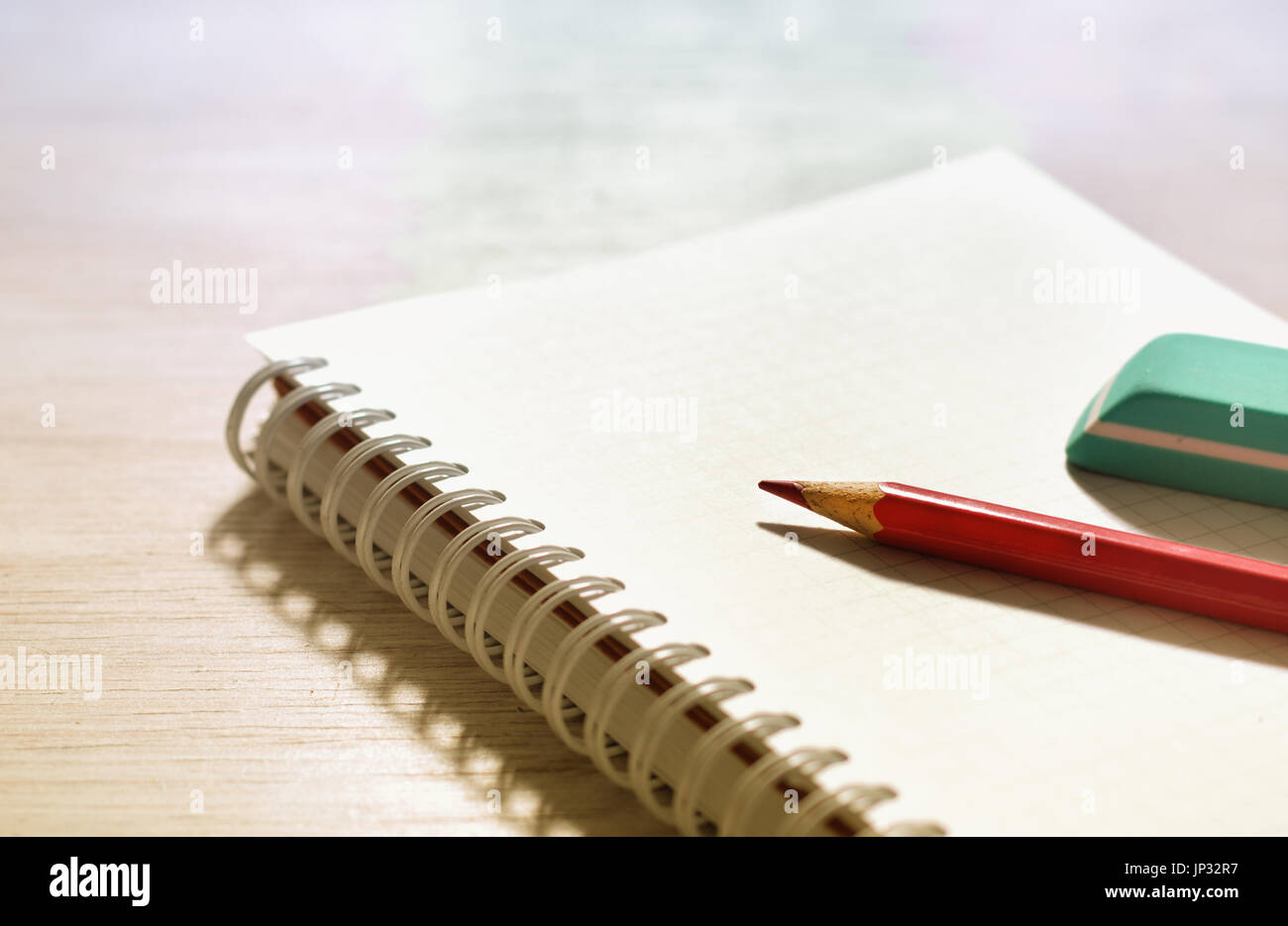 Red pencil and eraser on blank spiral notebook on desk. Place for your ...