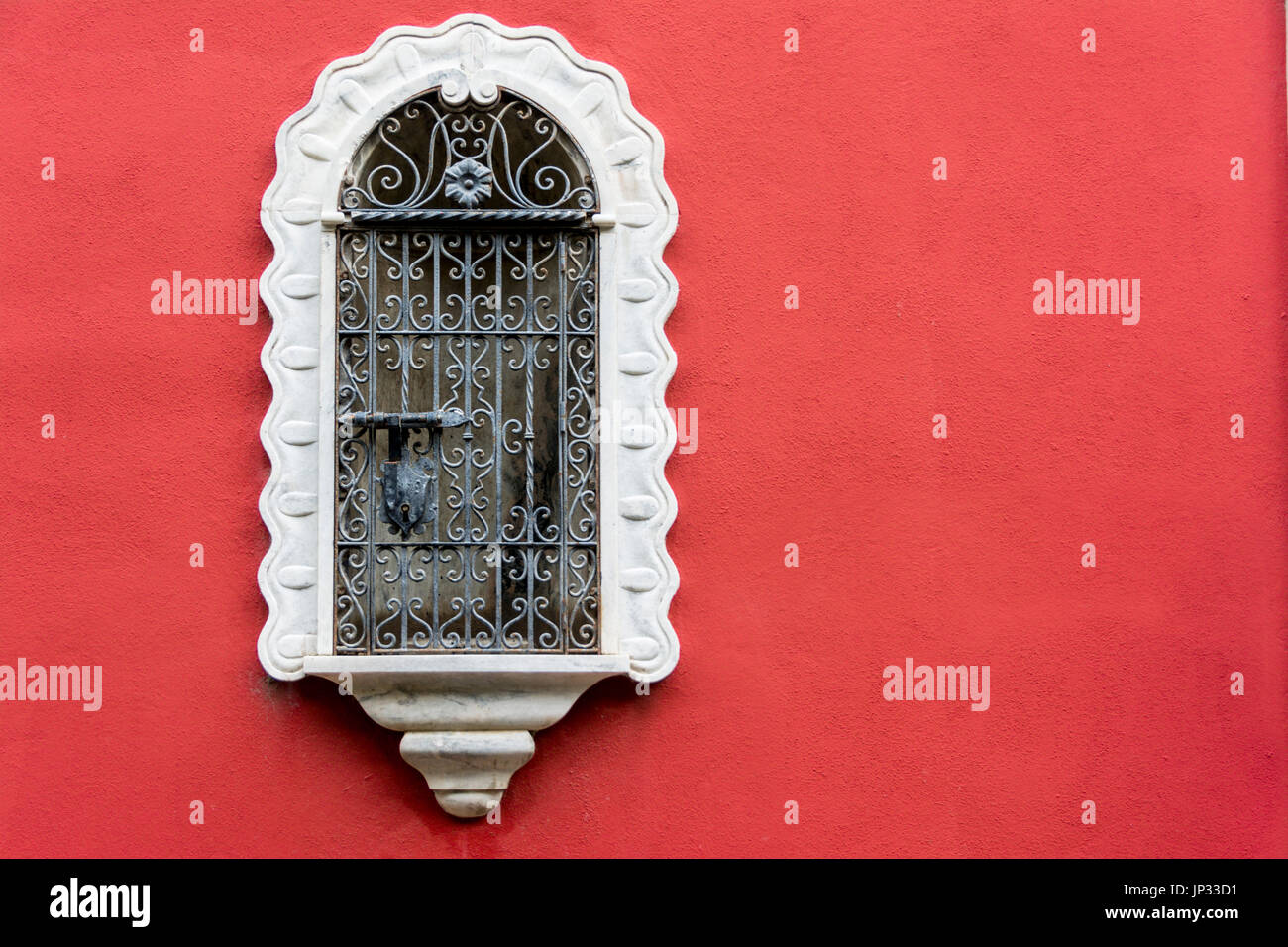 Antique medieval window with white iron bars and red wall in Seville ...
