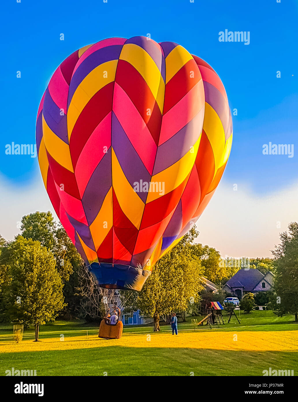Hot air balloon landing on the lawn in a residential area: houses in ...