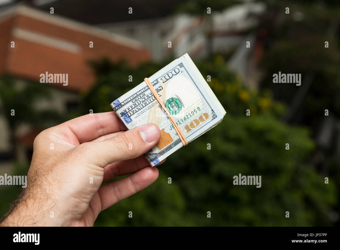 Hand of man holding dollar bills in front of a city landscape Stock ...