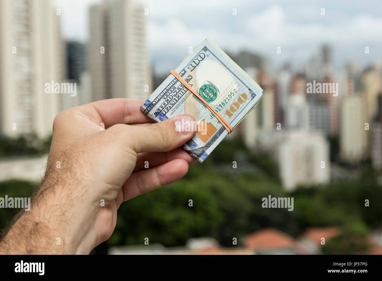 Hand of man holding dollar bills in front of a city landscape Stock ...