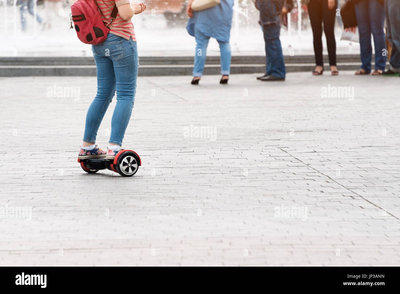 Young woman riding a hoverboard on the city square. New movement and ...