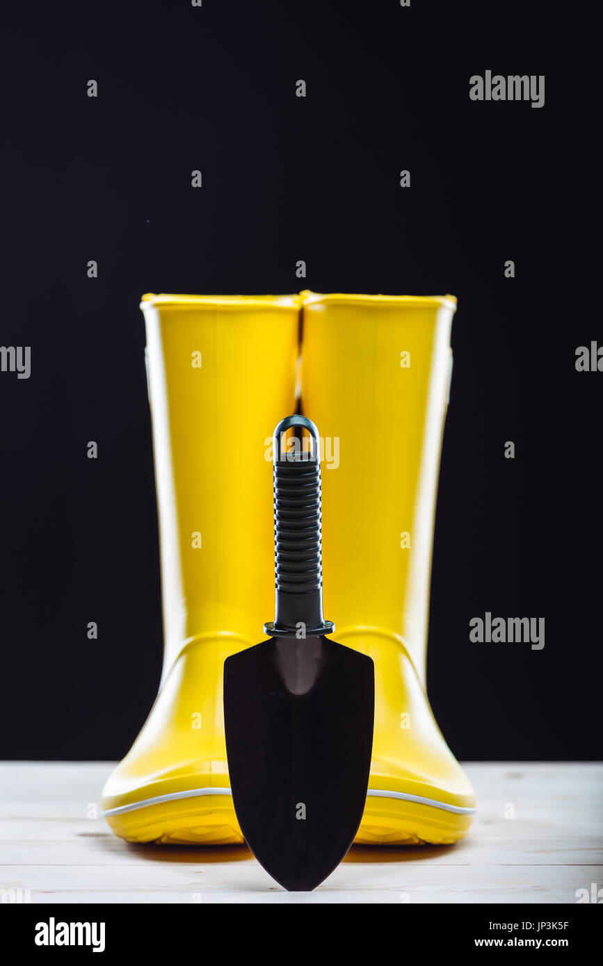 Close-up view of yellow rubber boots and small garden spade isolated on ...
