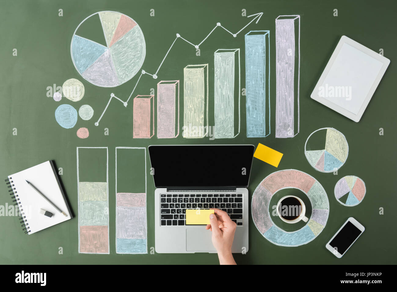 top view of human hand working on laptop near business charts with cup ...