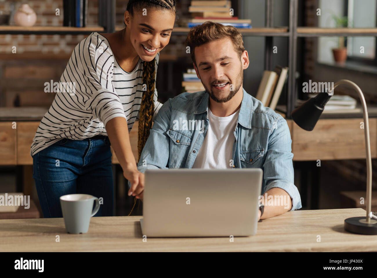 Positive delighted young woman pointing at monitor Stock Photo - Alamy