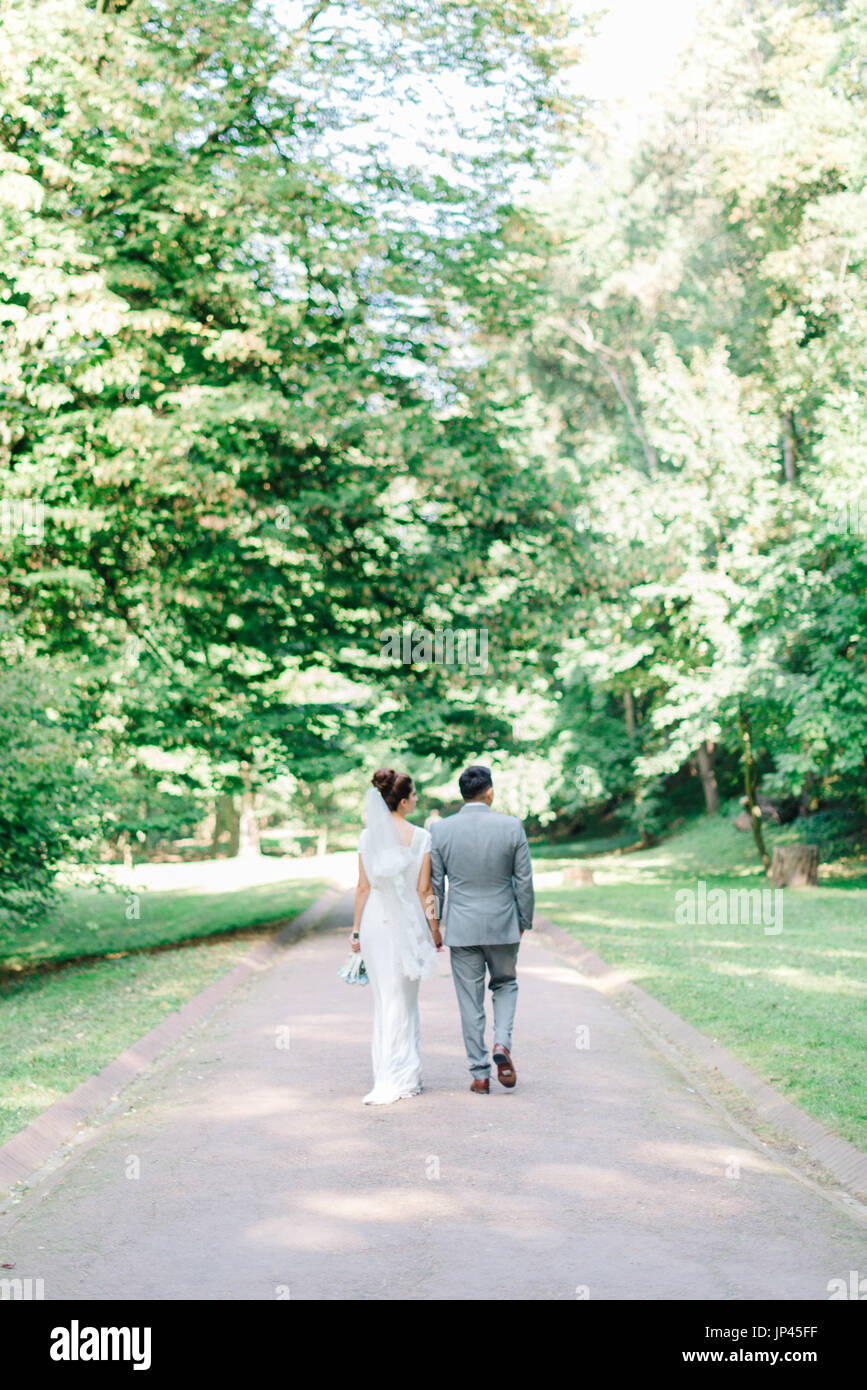 Look from behind at groom and bride walking along the path in gr Stock ...