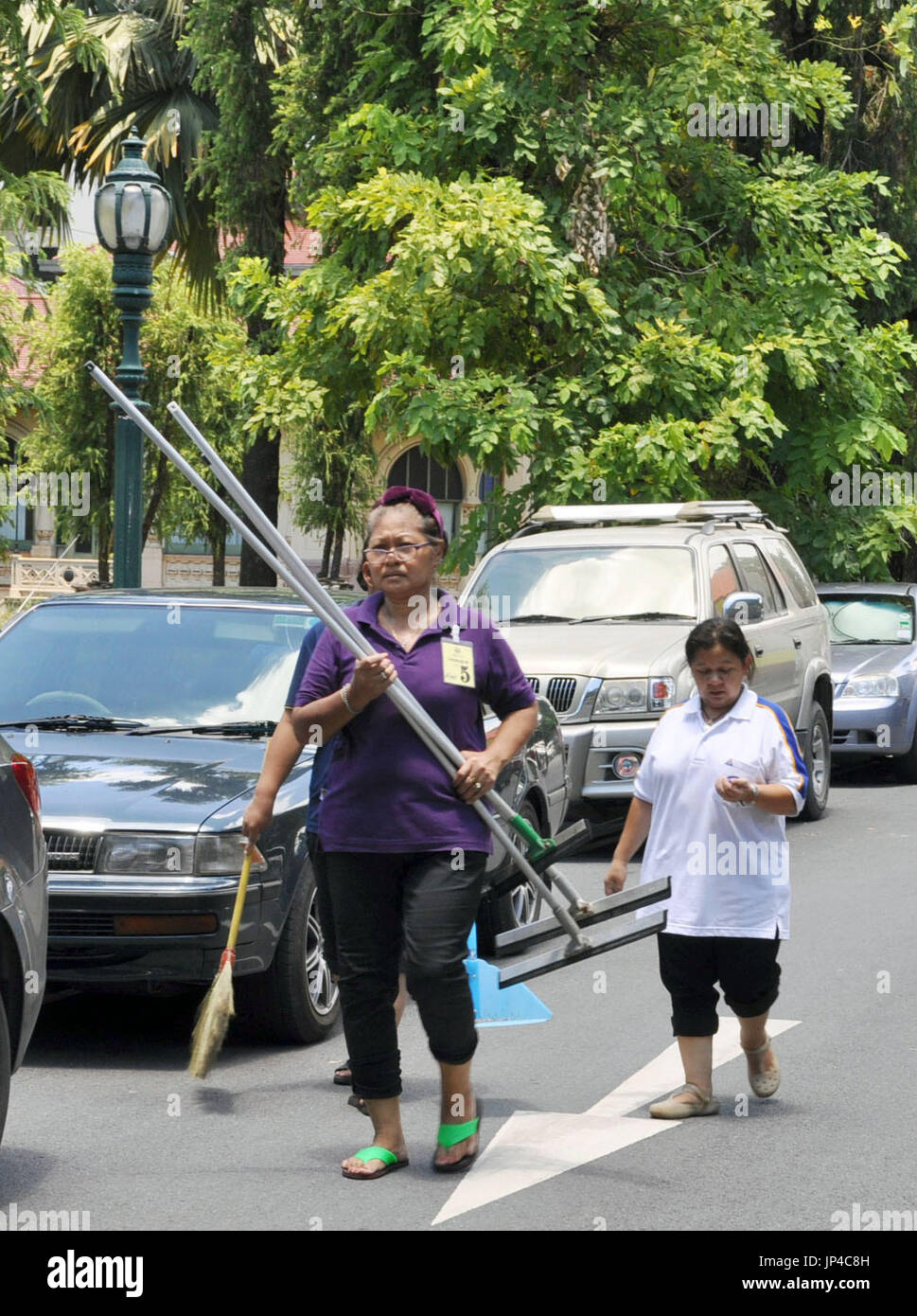 BANGKOK, Thailand - Cleaning staff members walk in the premises of the ...