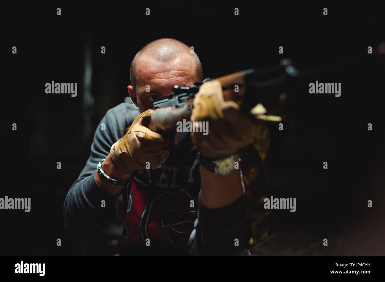 Athletic man in gray clothes with a carbine gun in his hand. Close-up ...