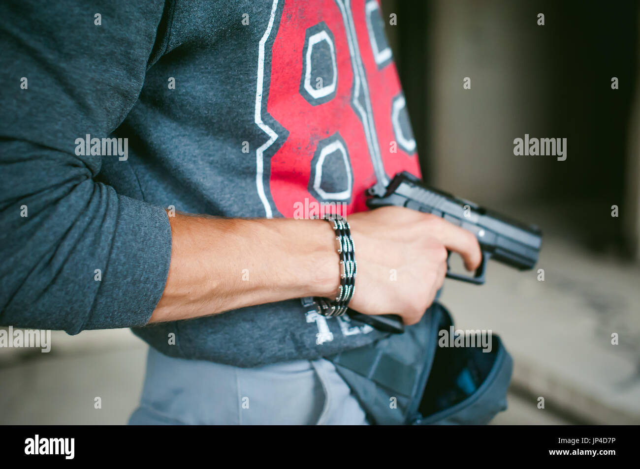man pulls a gun out of his bag, holding it in his hand Stock Photo - Alamy