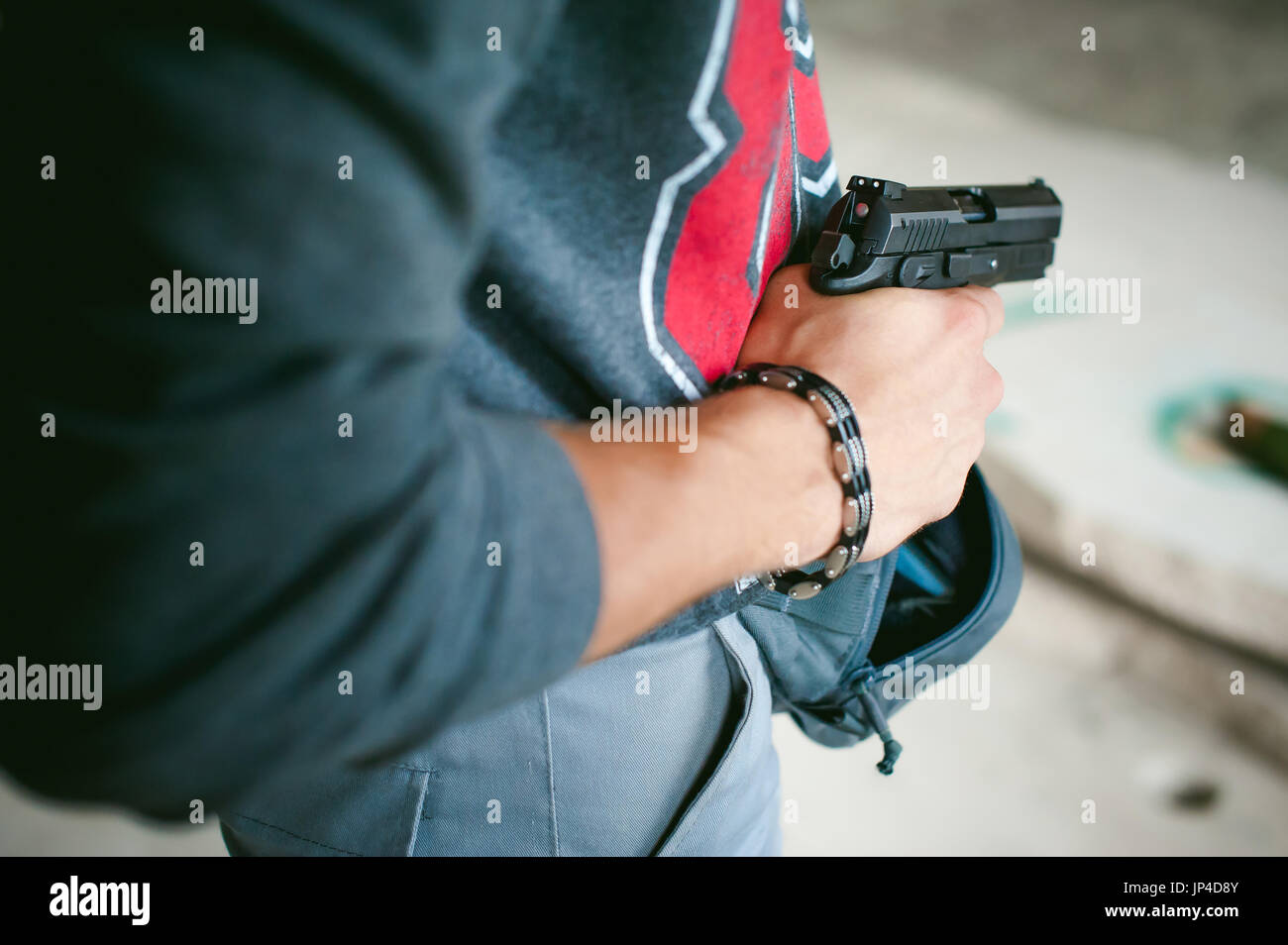 man pulls a gun out of his bag, holding it in his hand Stock Photo - Alamy