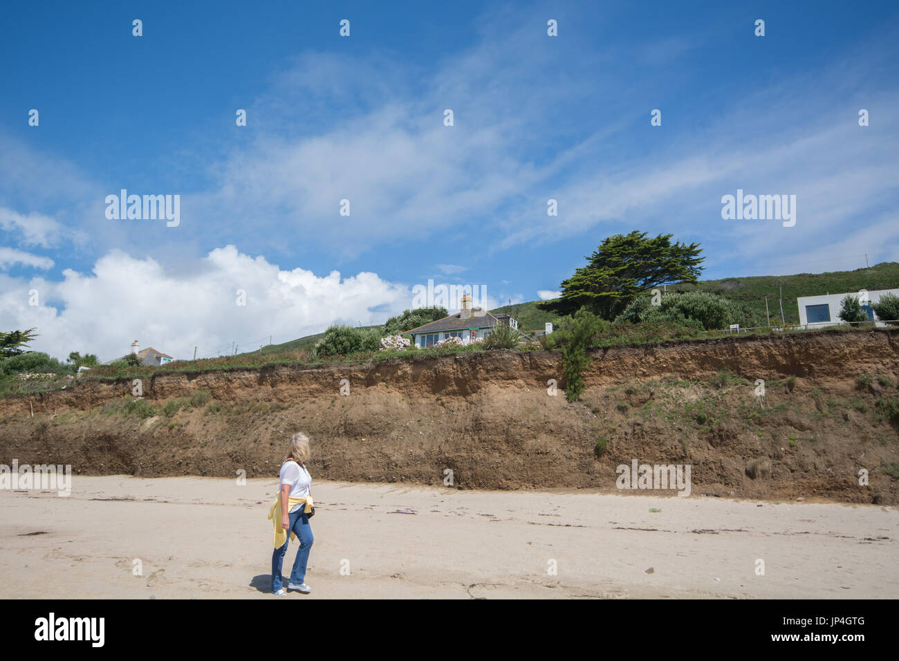 Walker on beach looking cliffside erosion Stock Photo - Alamy