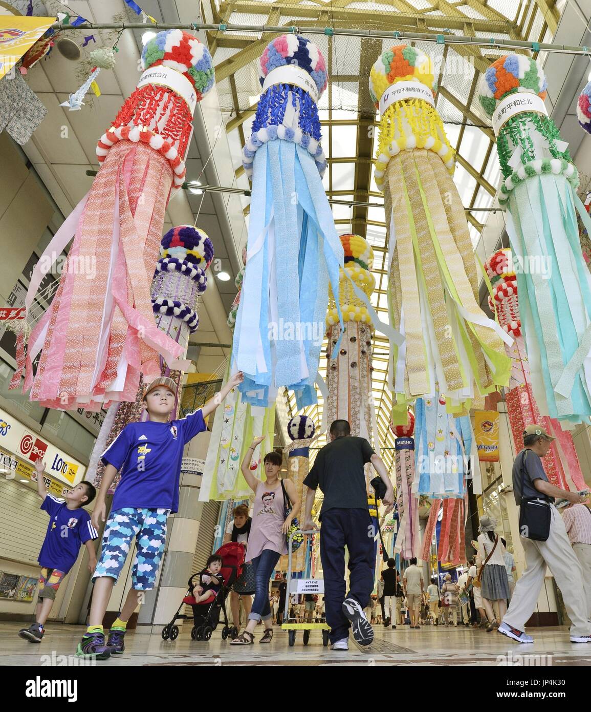 SENDAI, Japan - People walk under colorful streamers at a shopping ...