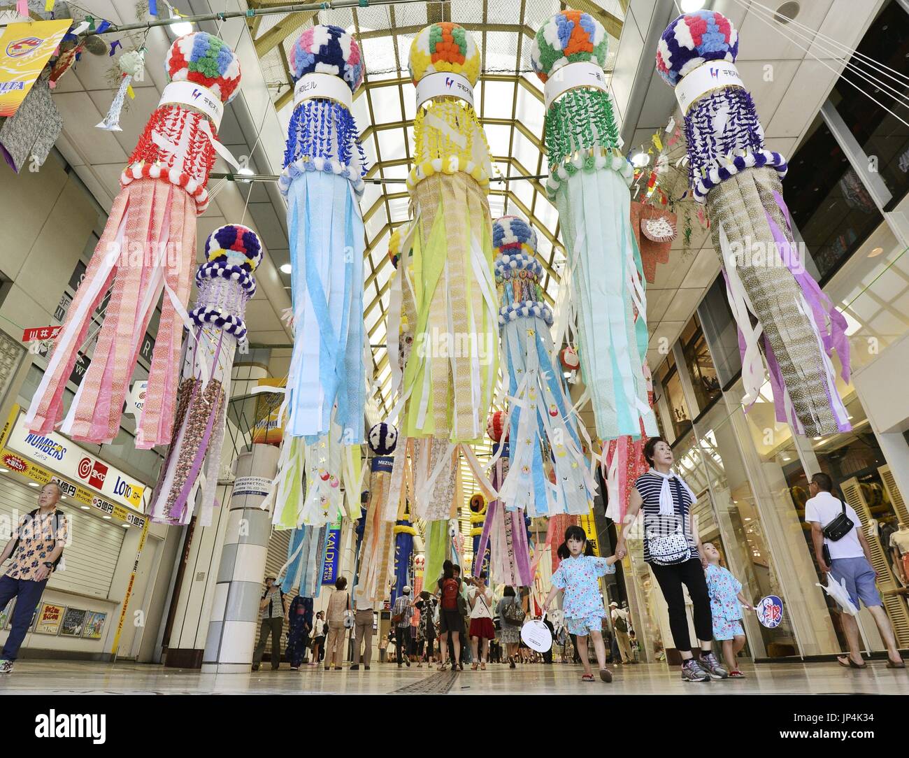 SENDAI, Japan - People walk under colorful streamers at a shopping ...