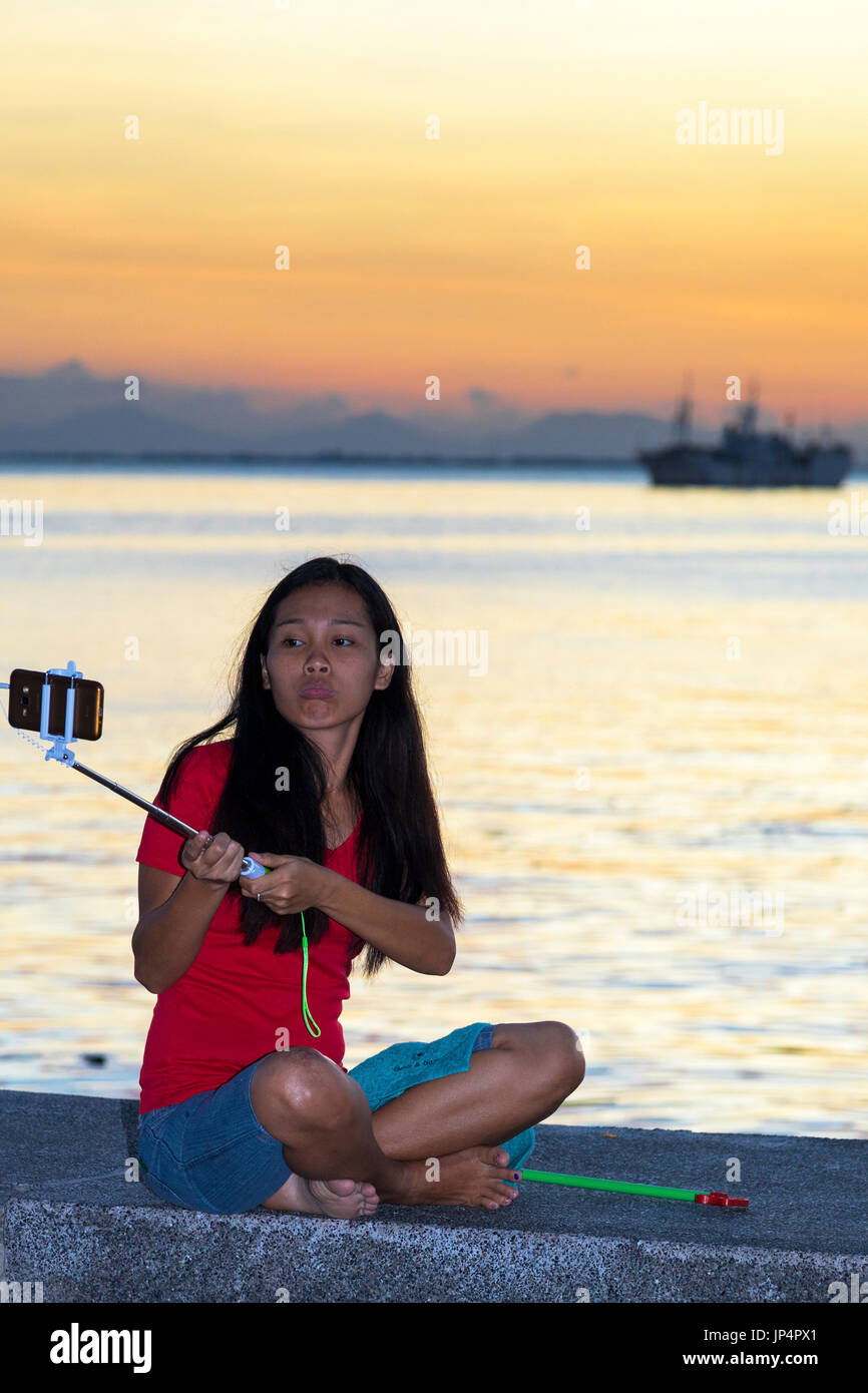 Girl taking selfie at sunset on Manila Bay, Roxas Boulevard ...