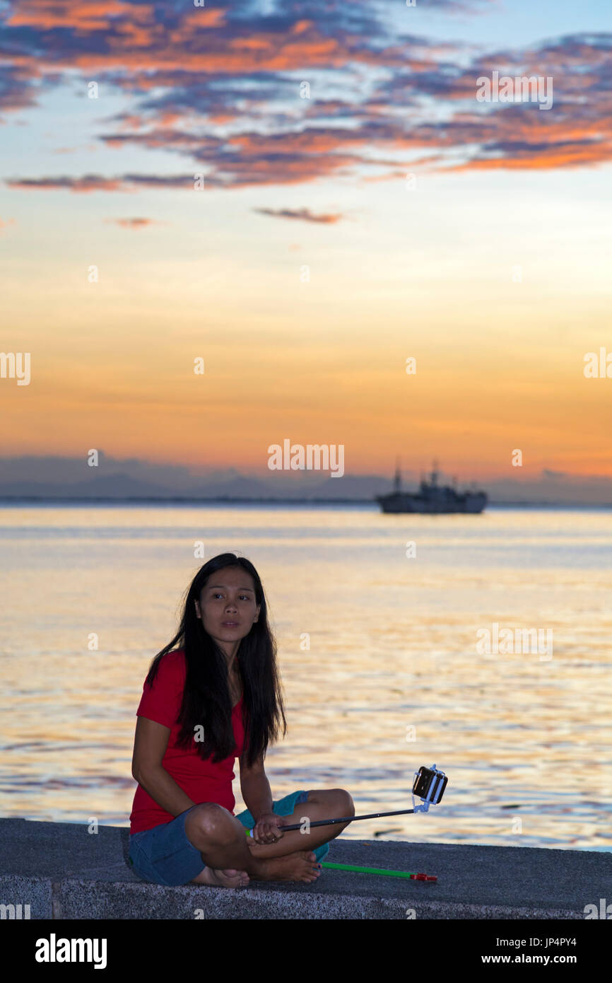 Girl taking selfie at sunset on Manila Bay, Roxas Boulevard ...