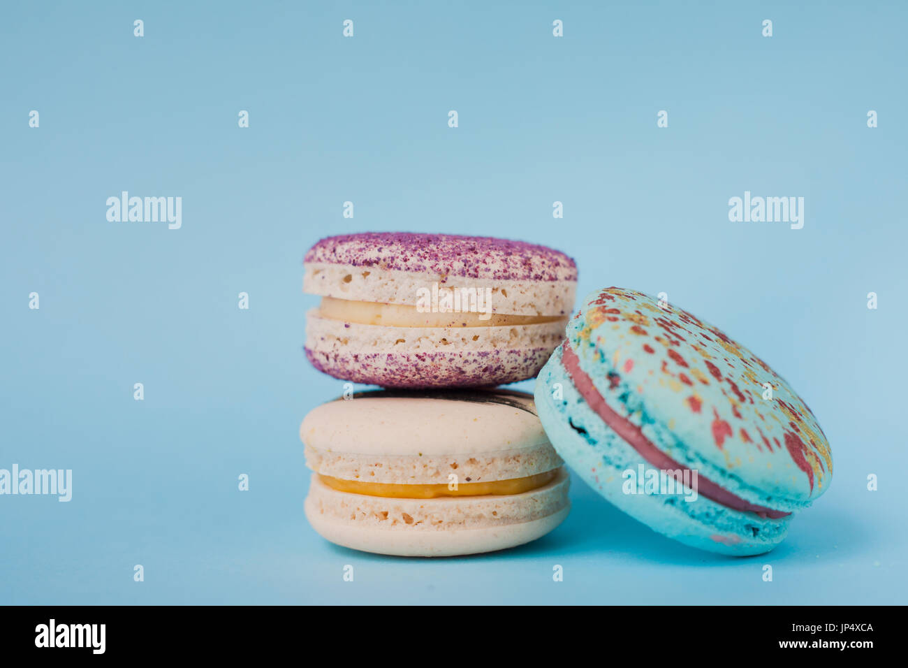 Different types of macaroons on blue background Stock Photo - Alamy