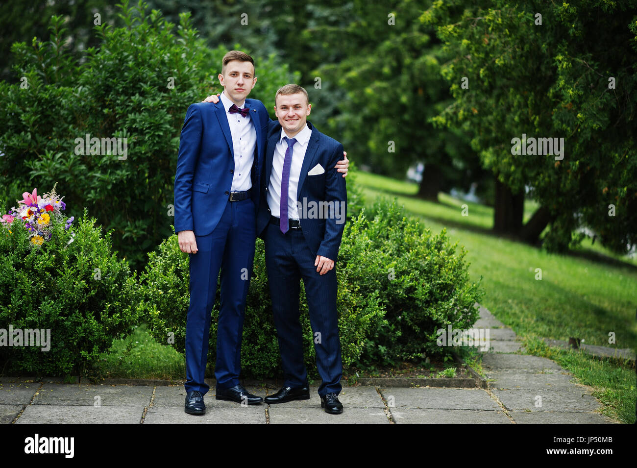 Two intelligent and handsome graduates in tuxedos posing on th ...
