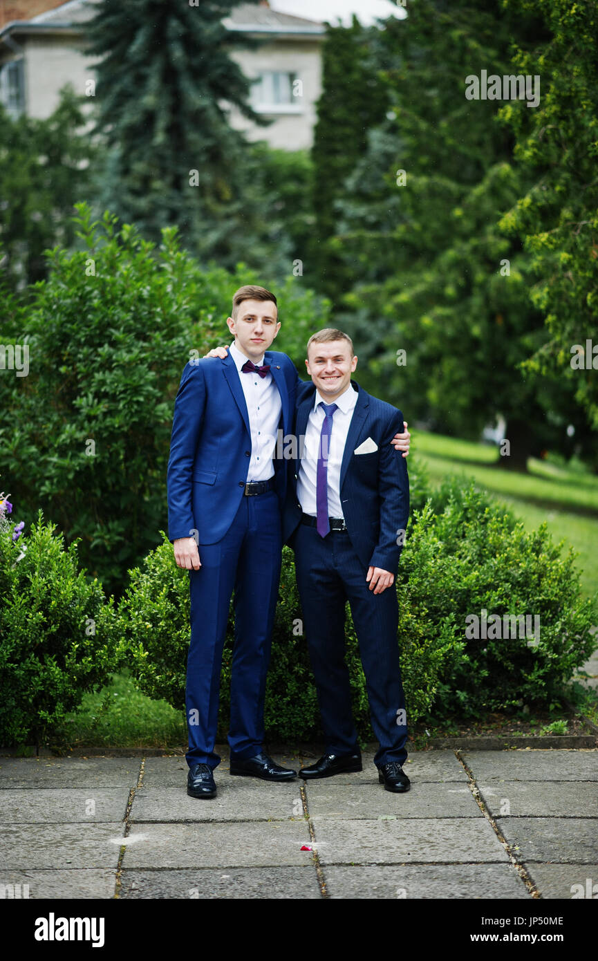 Two intelligent and handsome graduates in tuxedos posing on th ...