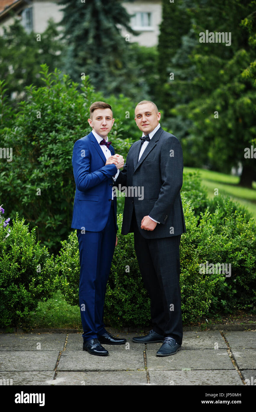 Two intelligent and handsome graduates in tuxedos posing on th ...
