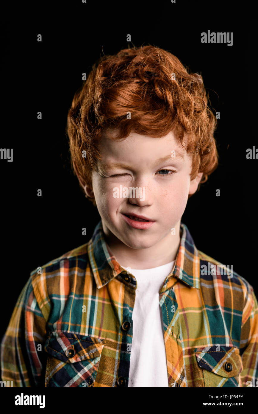 portrait of adorable redhead boy blinking isolated on black Stock Photo ...
