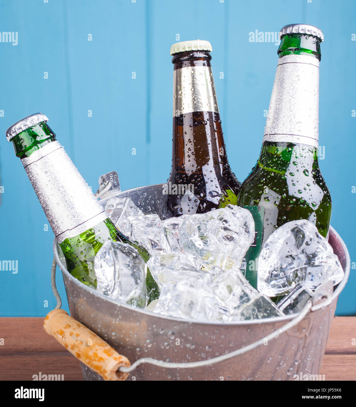 Three unopened bottles of beer inside metal bucket filled with iced ...