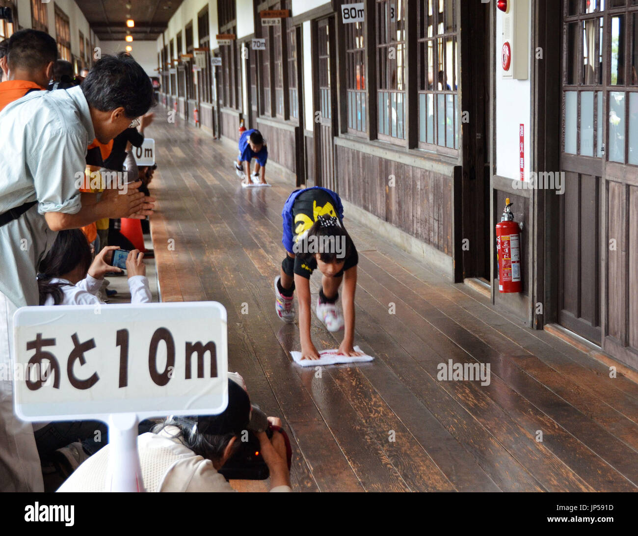 MATSUYAMA, Japan - Competitors clean the floor of a 109-meter corridor ...