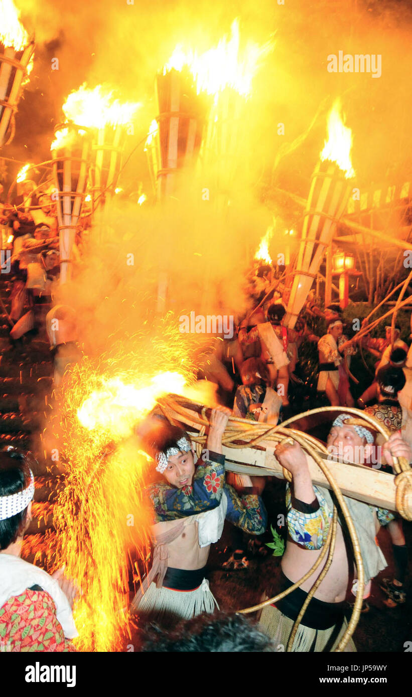 KYOTO, Japan - Fire sparks glitter as young men swing huge torches ...