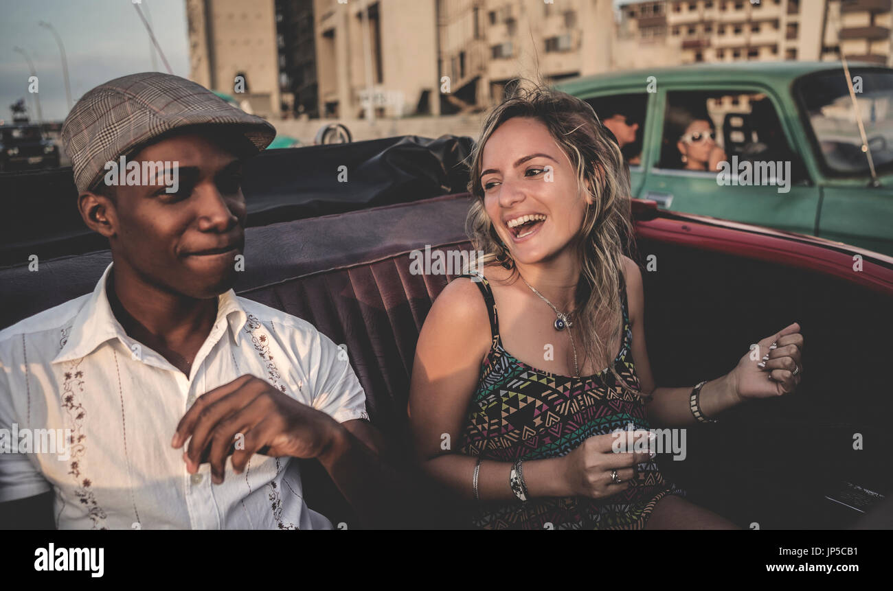 Two people riding through an urban environment in an open convertible ...