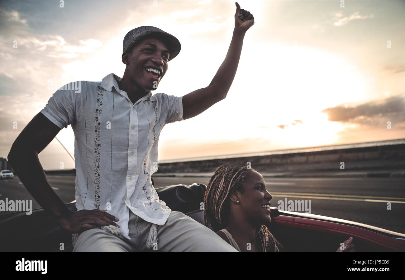 Two people riding through an urban environment in an open convertible ...