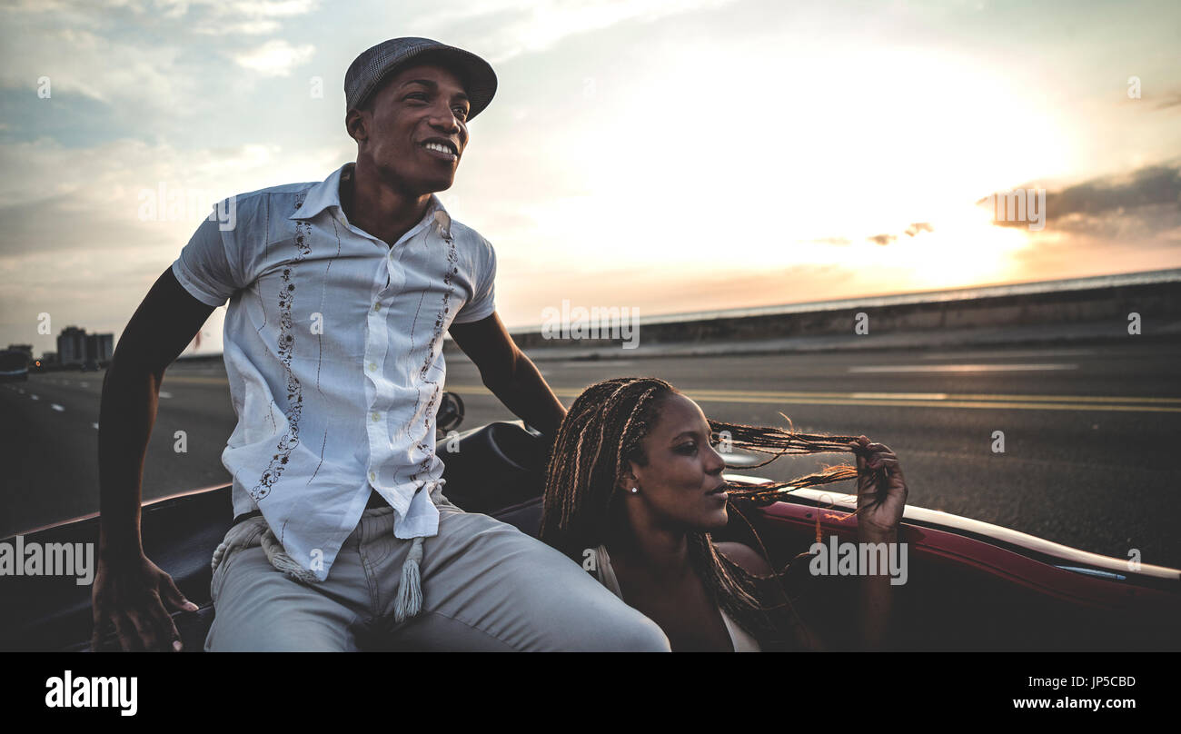 Two people riding through an urban environment in an open convertible ...