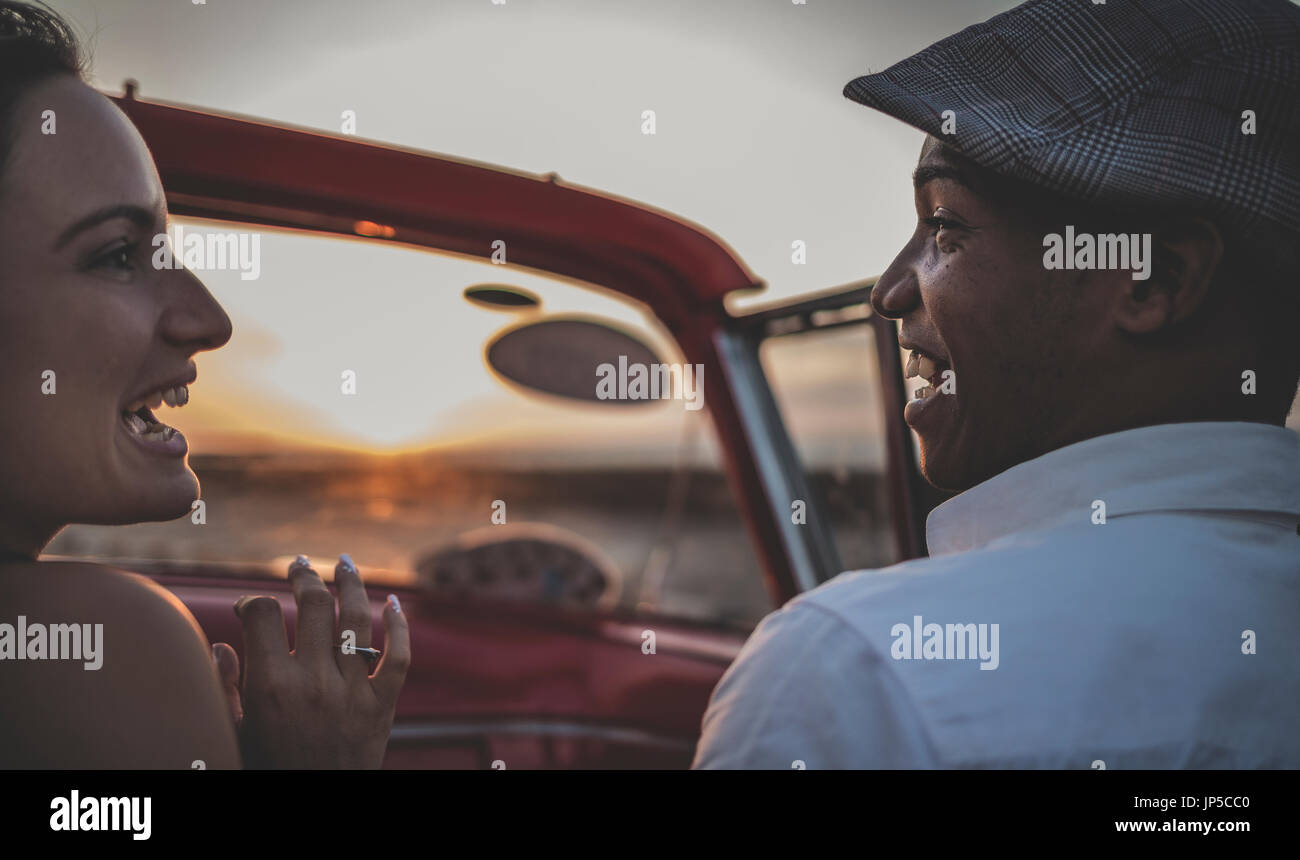 Two people riding in an open convertible classic car looking at each ...
