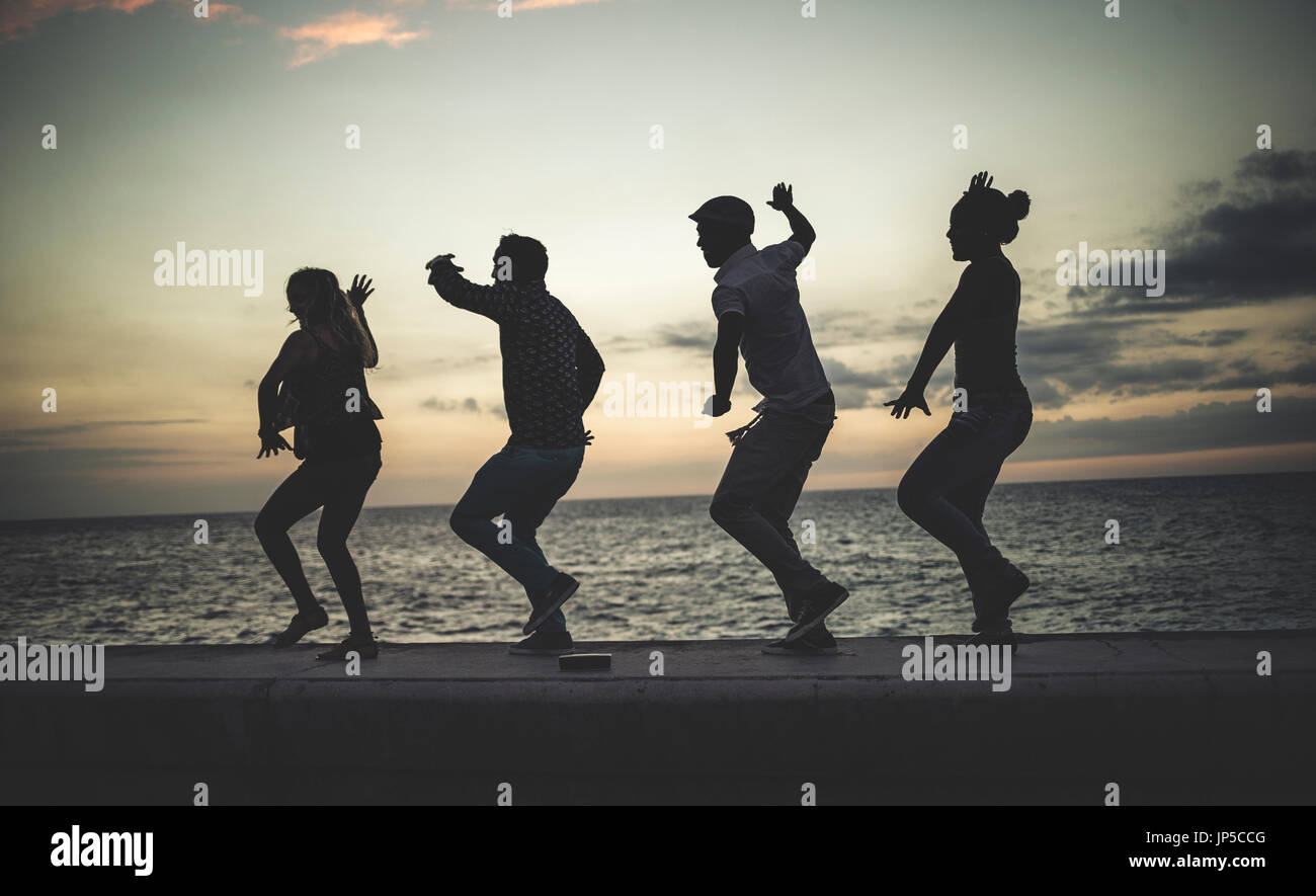 Four people dancing in a line on a sea wall in front of the ocean Stock ...