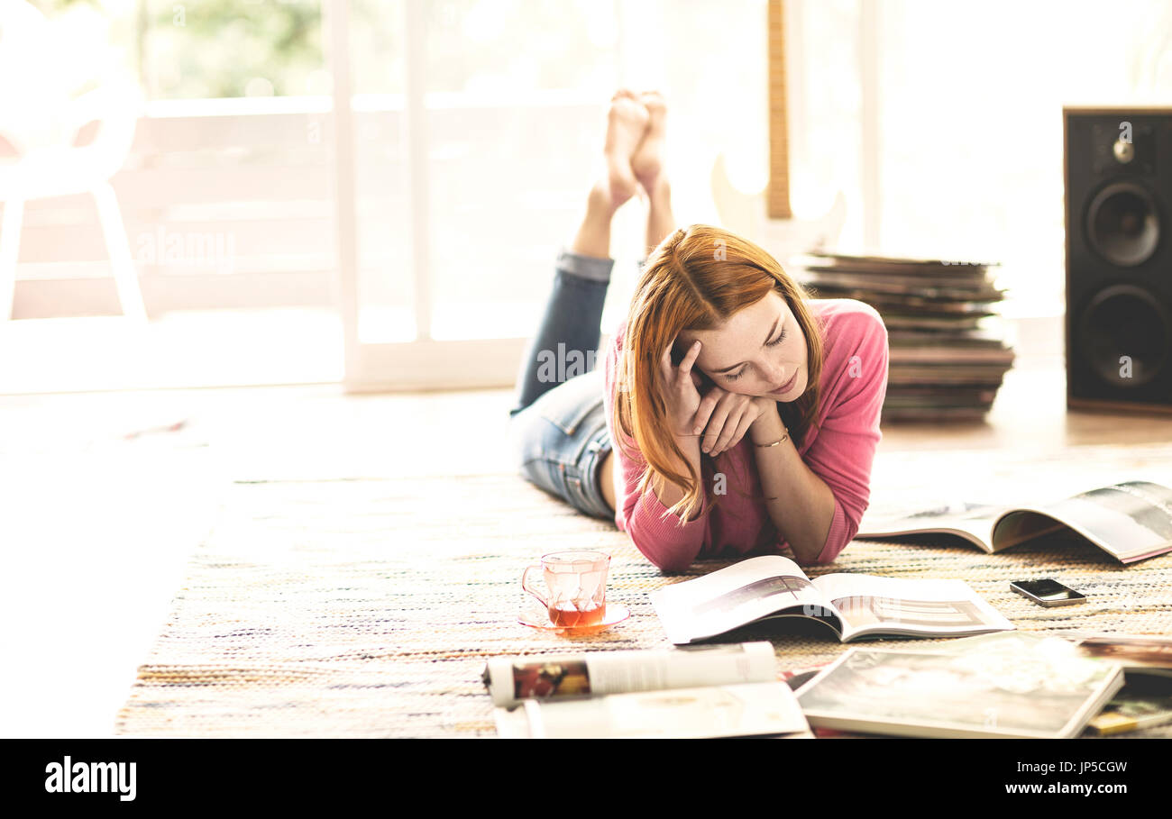 A woman lying on the floor reading a magazine Stock Photo - Alamy