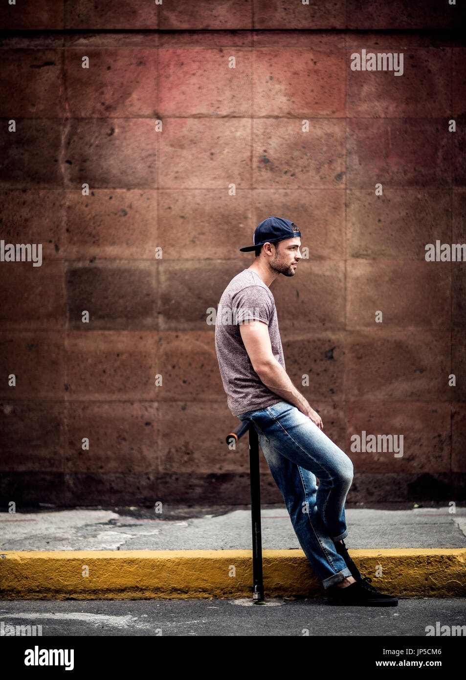 A man sitting on a piece of street furniture in a street Stock Photo ...