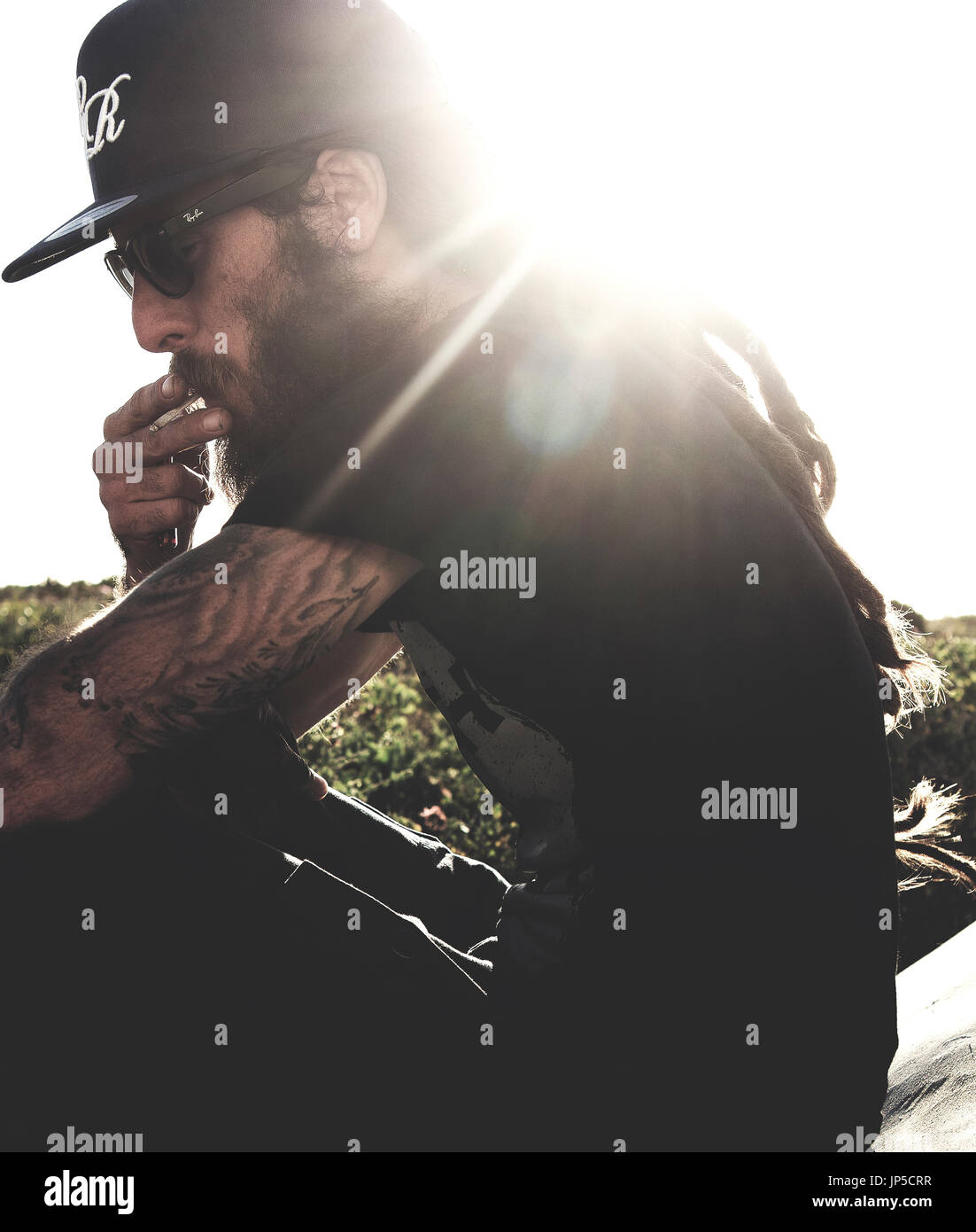 Side view of bearded man wearing baseball cap and sunglasses, smoking ...