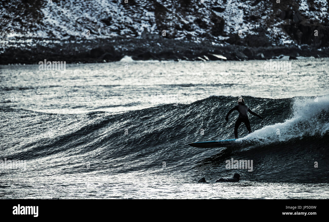 A young man surfing on an ocean with a mountain behind Stock Photo - Alamy