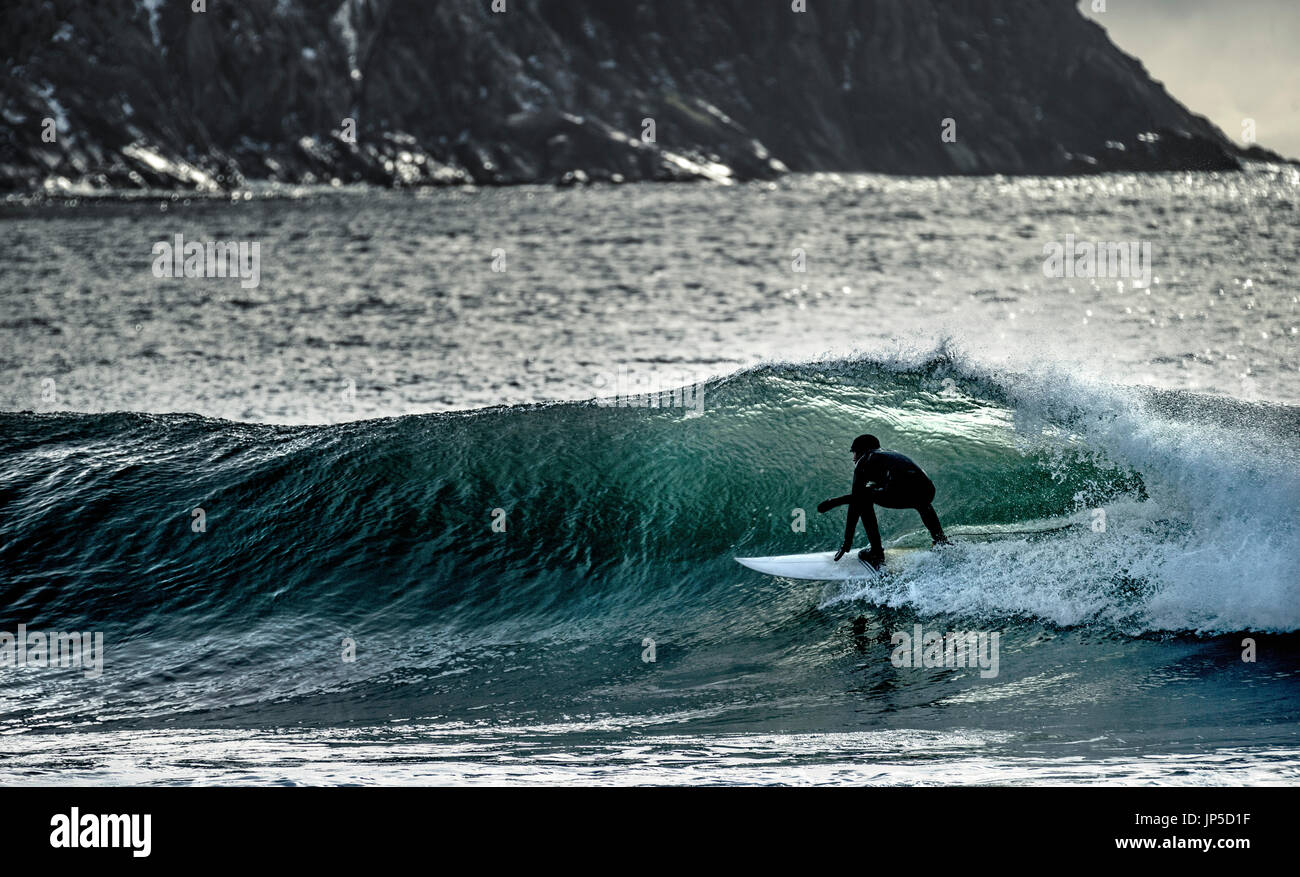 Young man surfing with a mountain behind Stock Photo - Alamy