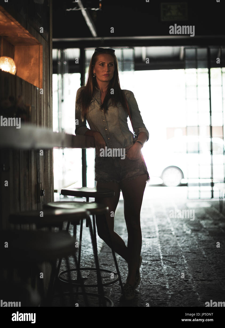 A young woman leaning against a bar Stock Photo - Alamy