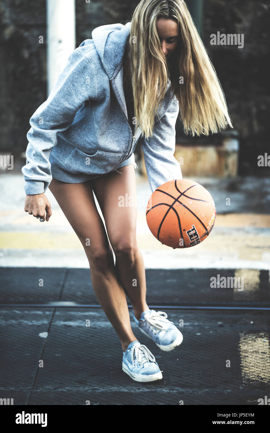Young woman standing and bouncing a basketball Stock Photo - Alamy