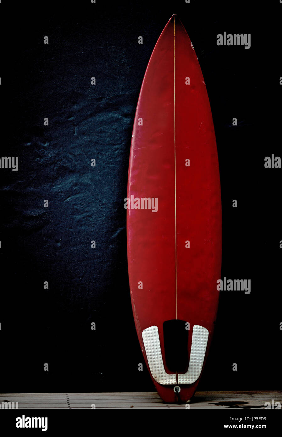 Red surfboard leaning against a black wall Stock Photo - Alamy