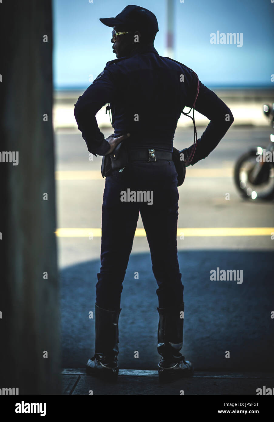 Rear view of man in uniform with cap and radio and weapons belt ...