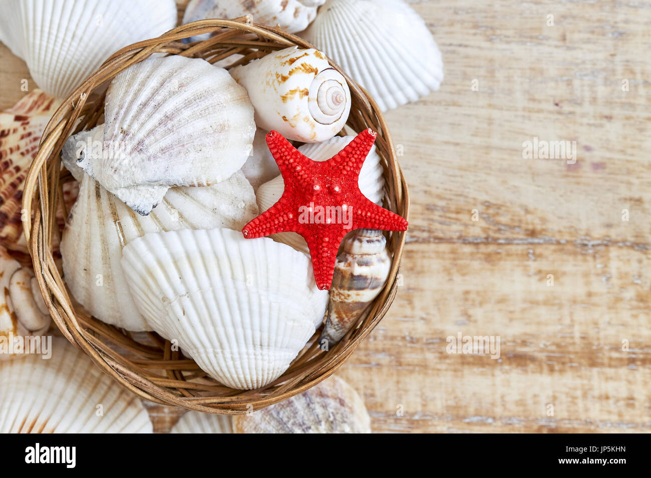 Various seashells in woven basket on rustic background. Top view with ...